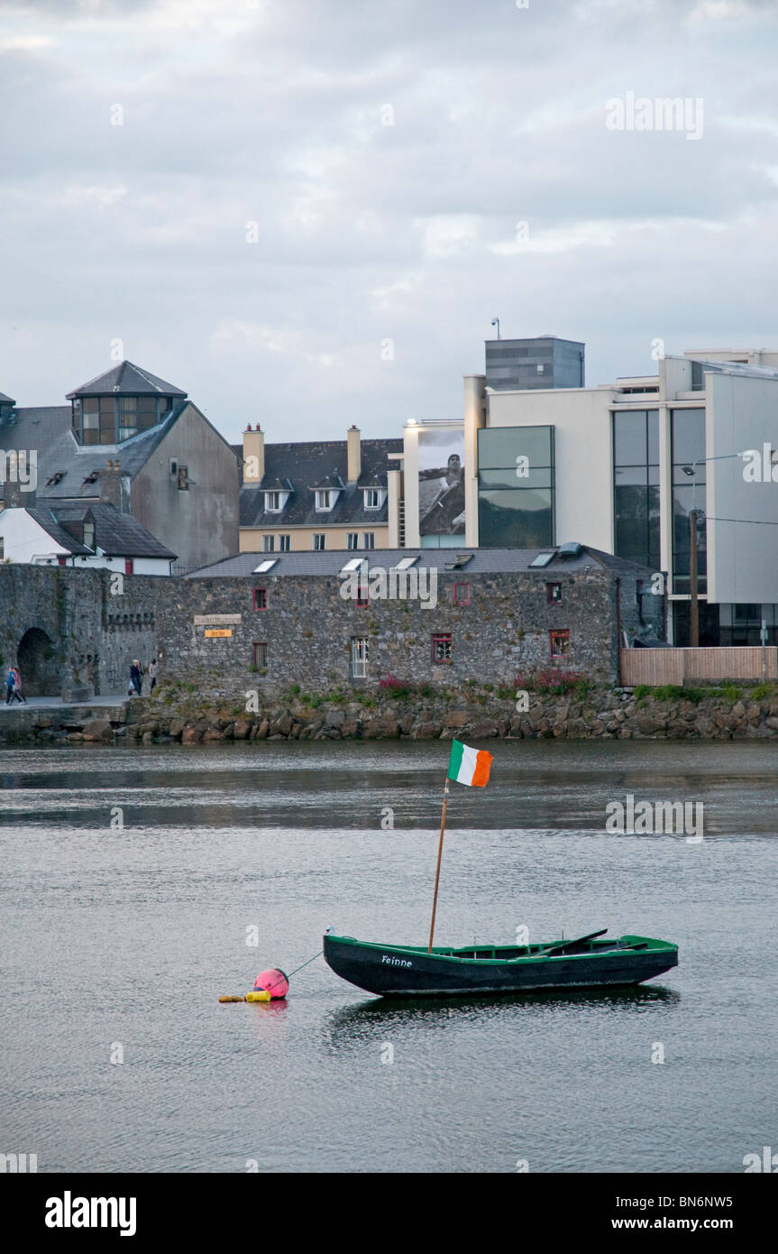 A small sailing boat flying the Irish flag floats in Galway harbour ...