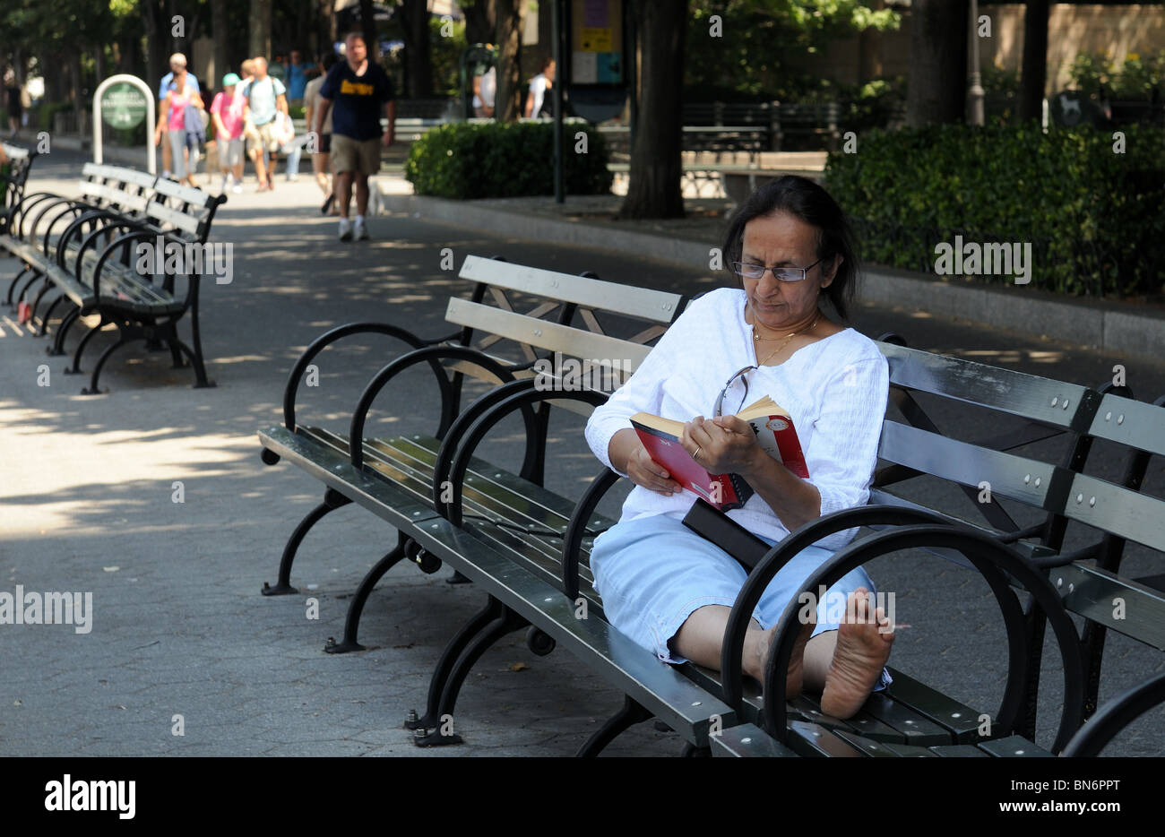 A woman reading a book on a park bench in Lower Manhattan Stock Photo ...