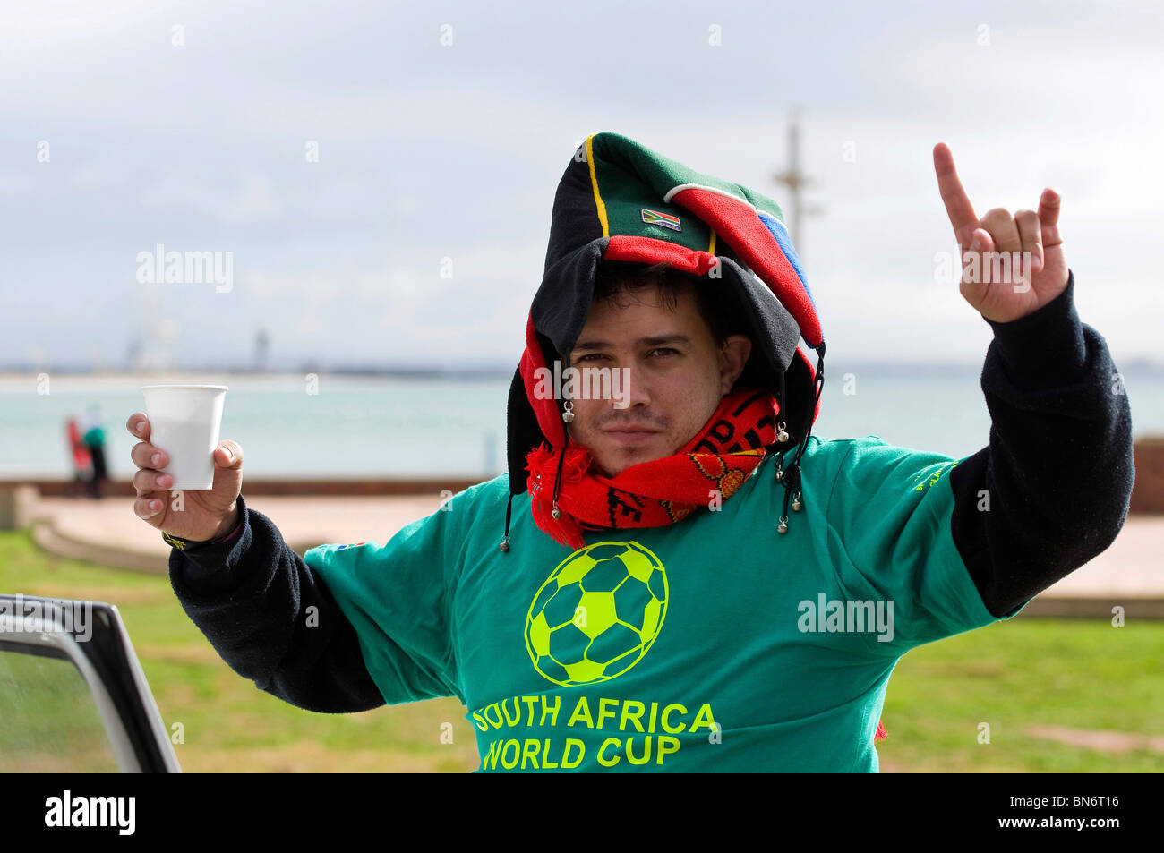 South African soccer fan keeps warm on a winter's day in Port Elizabeth ...