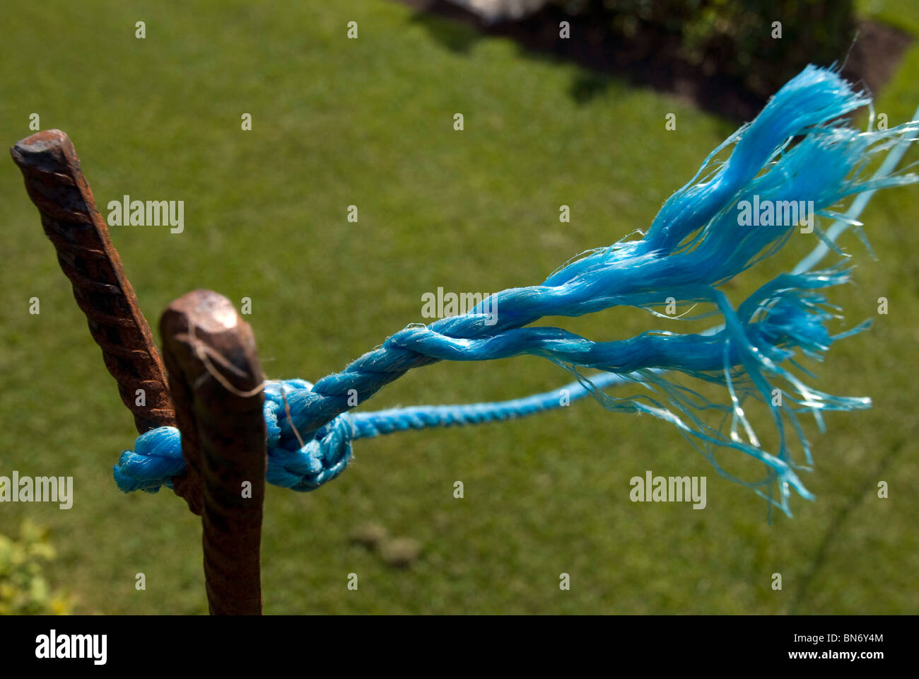 Blue, fraying nylon string tied to a metal post Stock Photo - Alamy