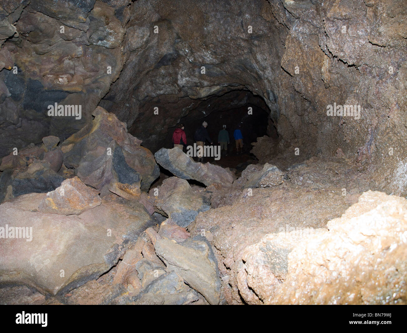 Hikers explore a cave formed by lava flows inside a former volcano, St ...