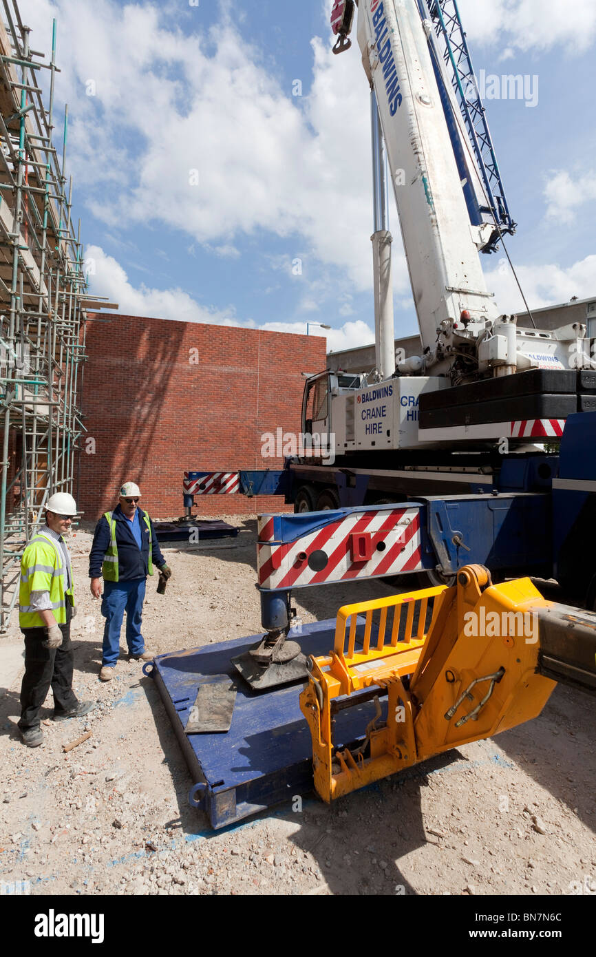Setting up outriggers for a tall mobile crane on a construction site ...