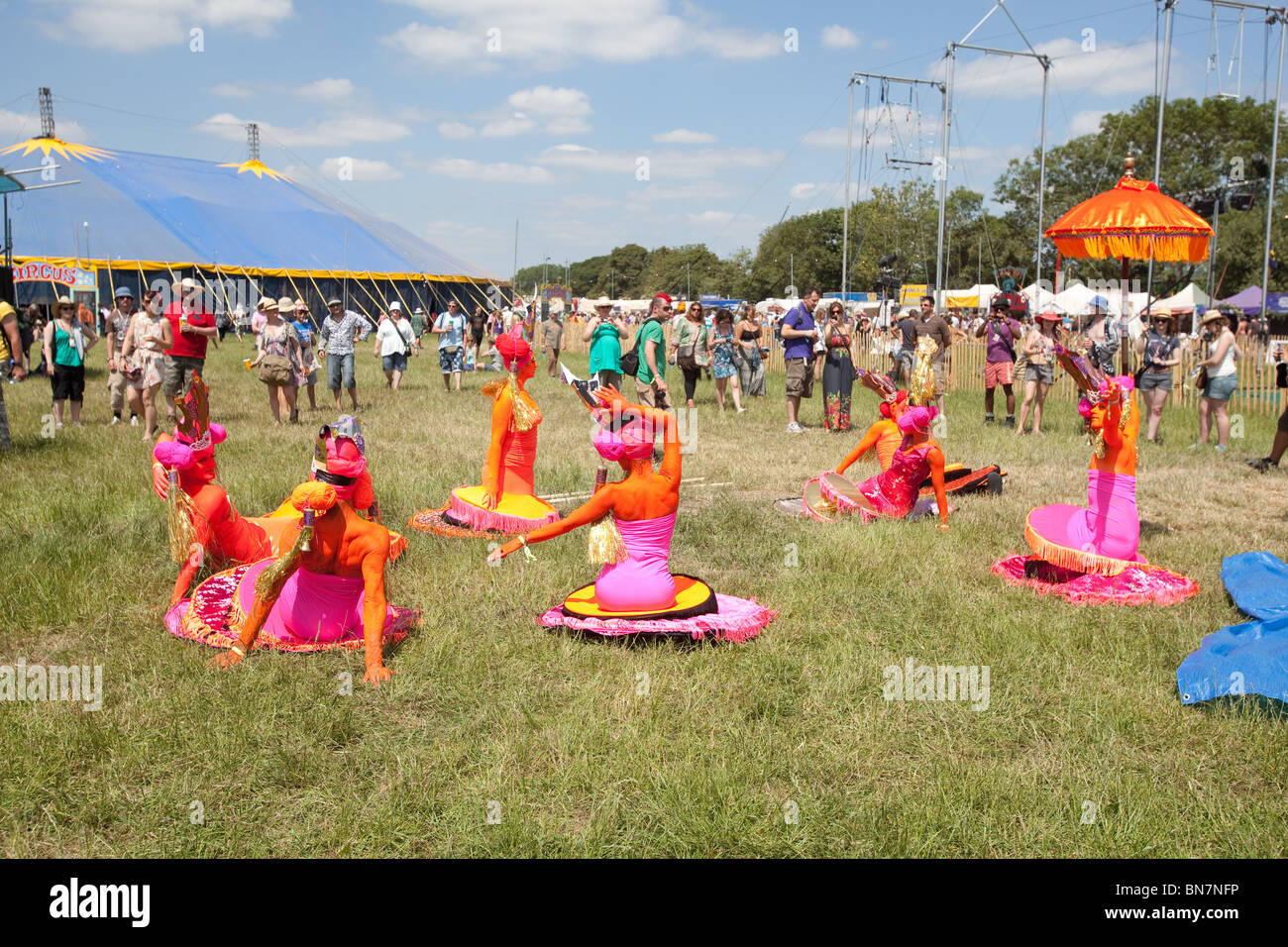 Bright orange cabaret performers in the circus field at the Glastonbury ...