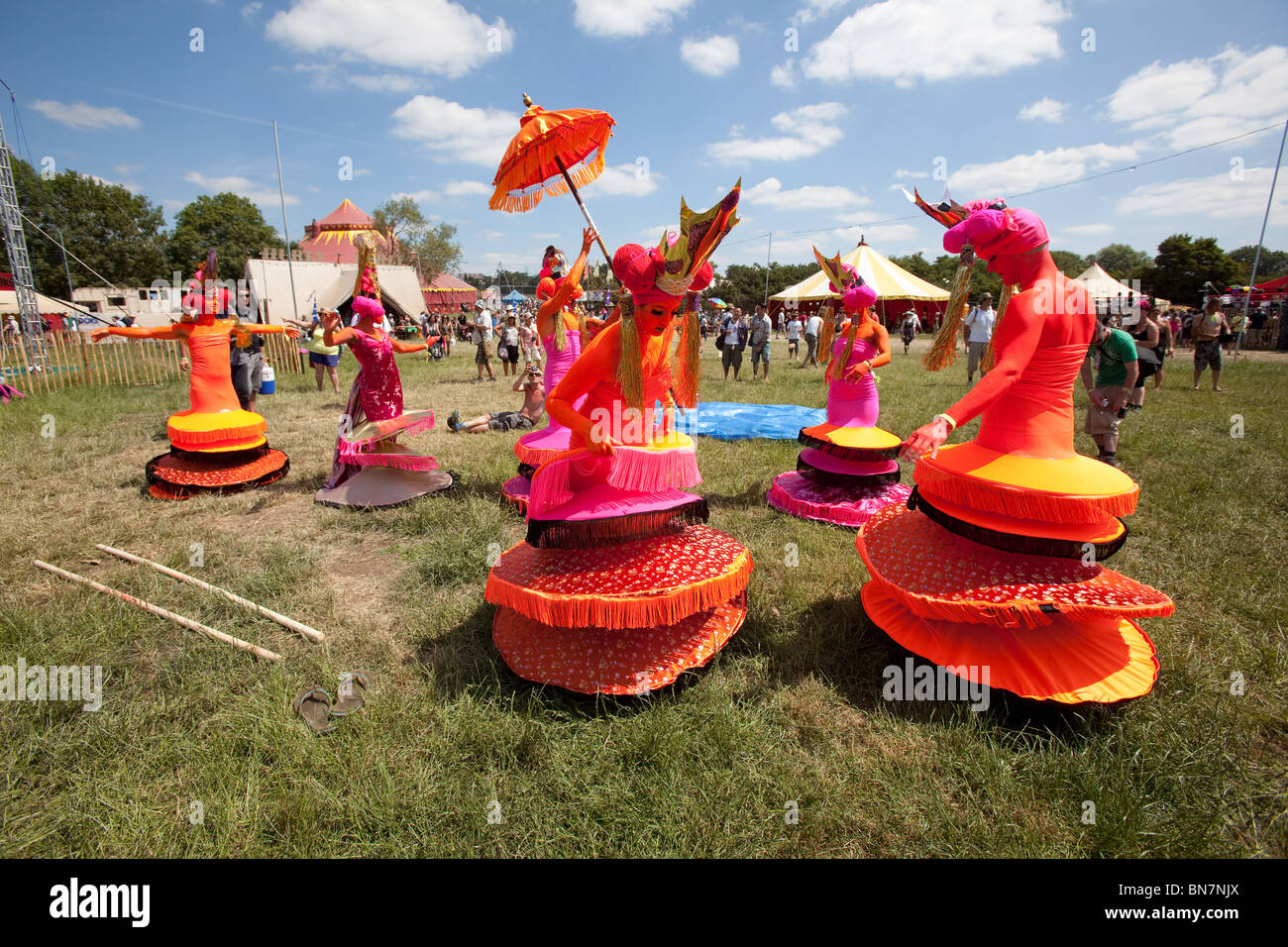 Bright orange cabaret performers in the circus field at the Glastonbury ...
