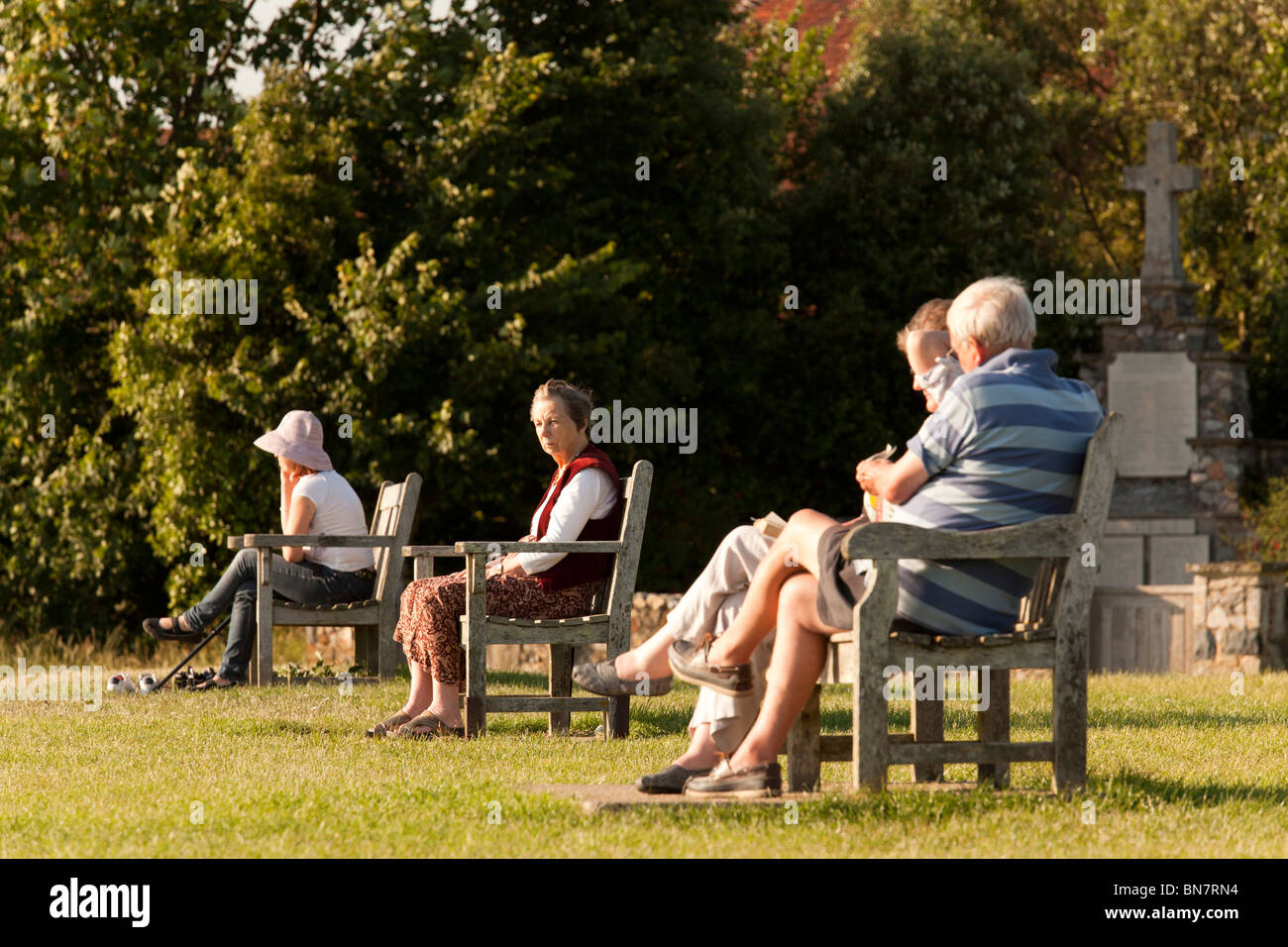 seated people enjoying the evening sunshine on benches at Bosham Stock ...