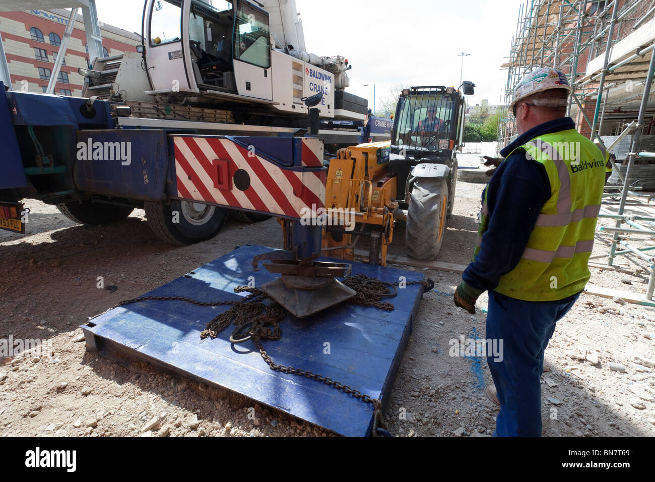 Setting up outriggers for a tall mobile crane on a construction site ...