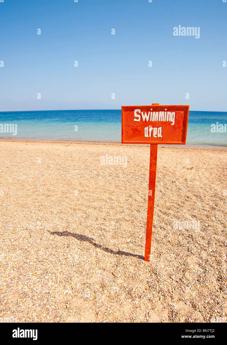 View out to sea from a tropical beach with a swimming area sign Stock ...