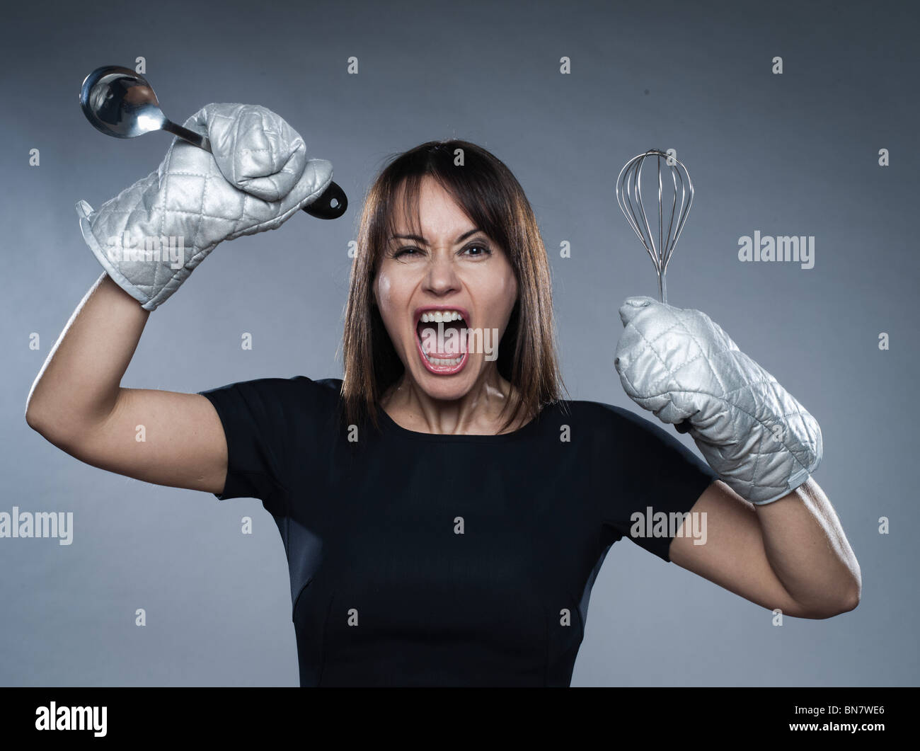 woman strain holding kitchen utensils isolated studio on grey ...