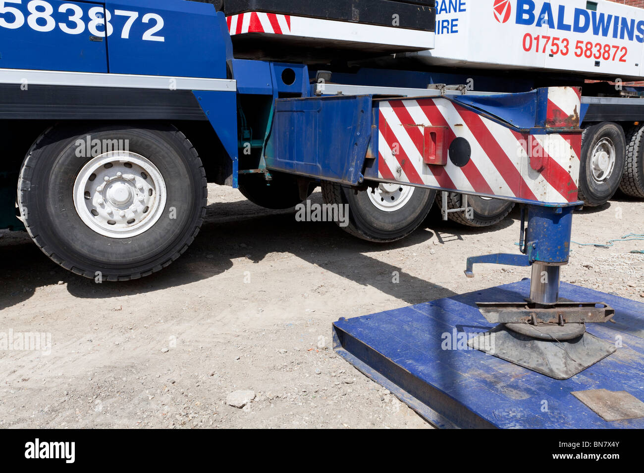 Setting up outriggers for a tall mobile crane on a construction site ...