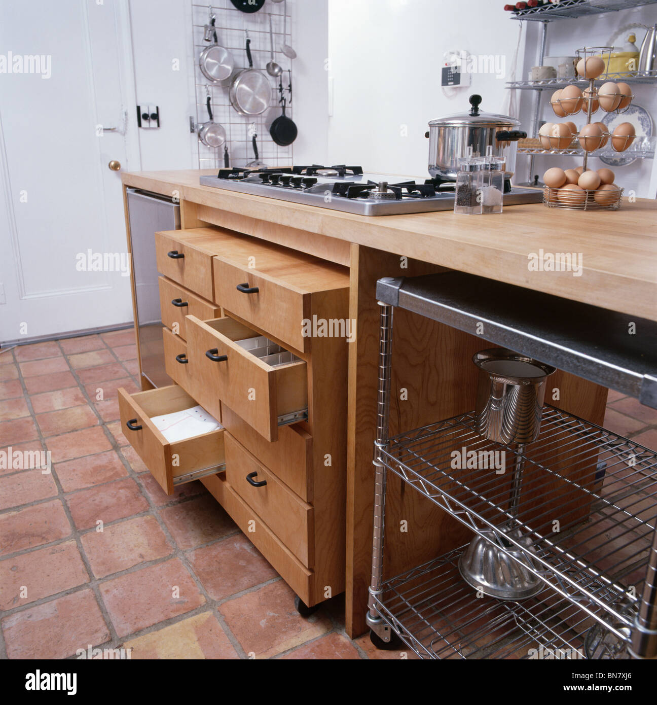 Fitted wooden storage drawers beside range oven in modern kitchen with ...