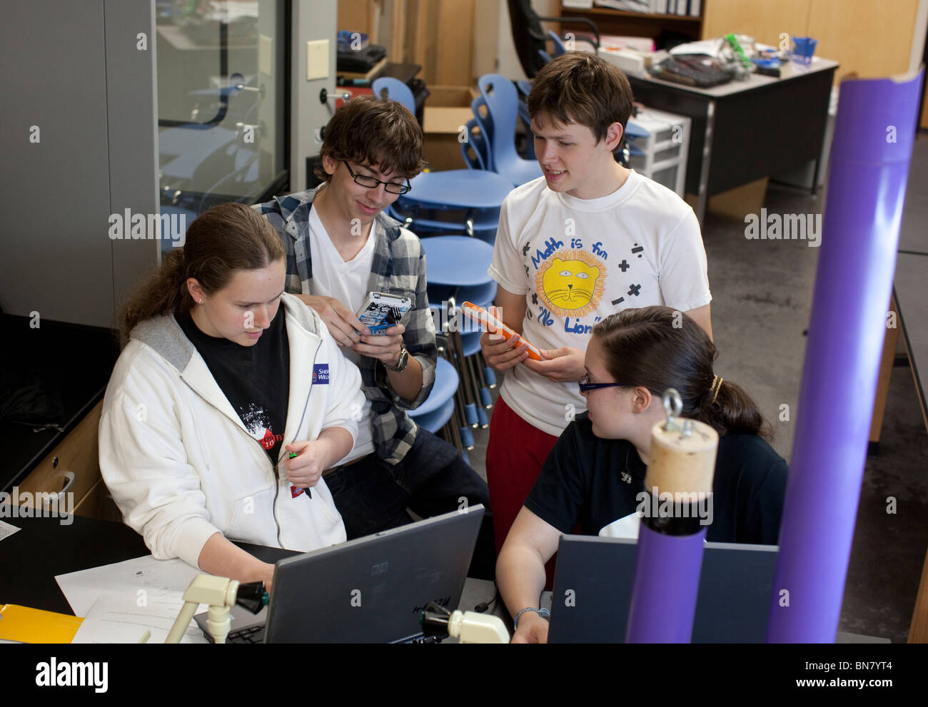 High school students collaborate in class using laptop computers to do ...