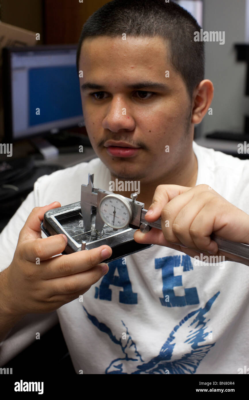Hispanic high school boy uses a caliper to take a measurement in ...