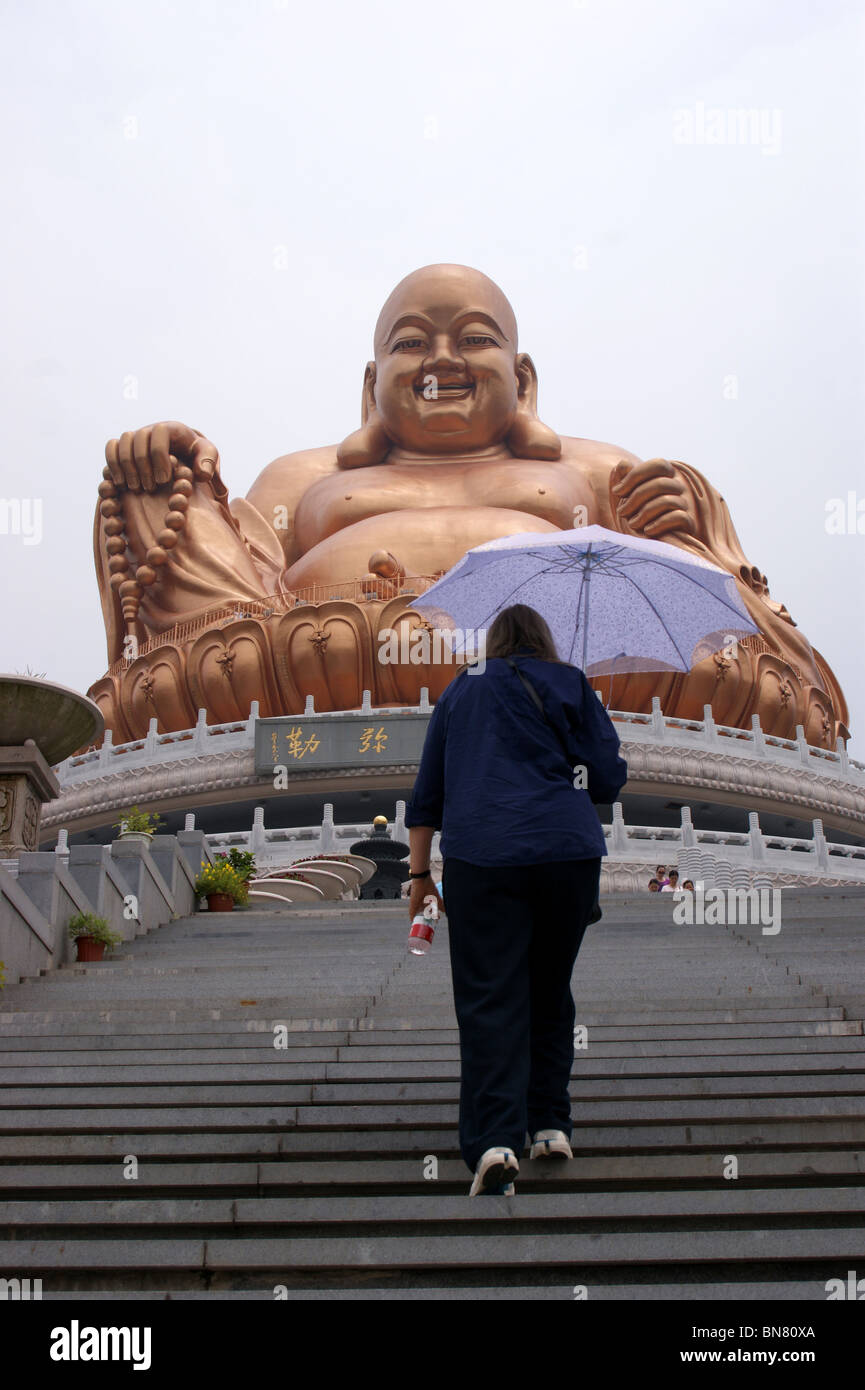 A woman with parasol climbing steps to statue of Maitreya Buddha ...