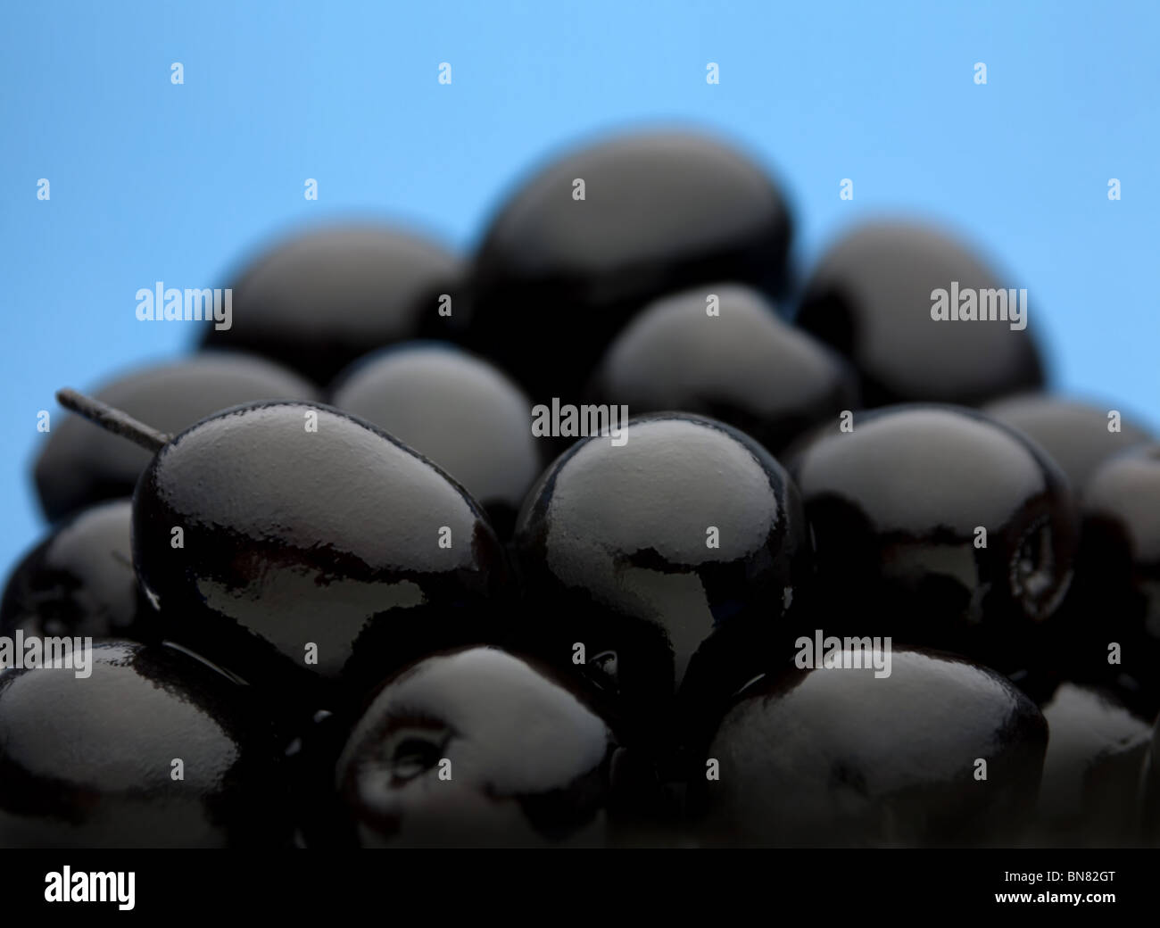 Black olive vegetable closeup on blue background Stock Photo - Alamy