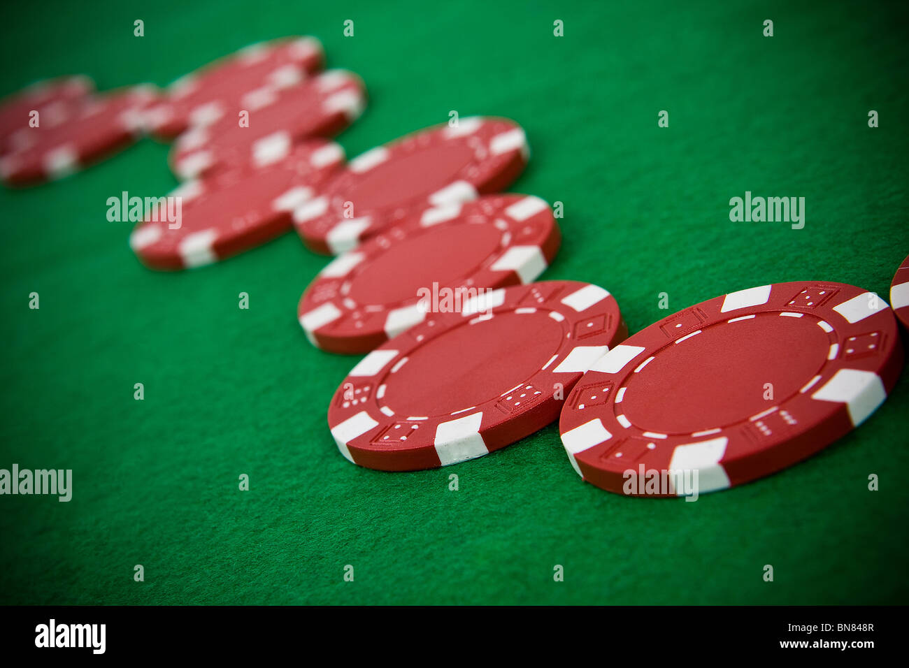 Line of red poker chips on green poker table Stock Photo - Alamy