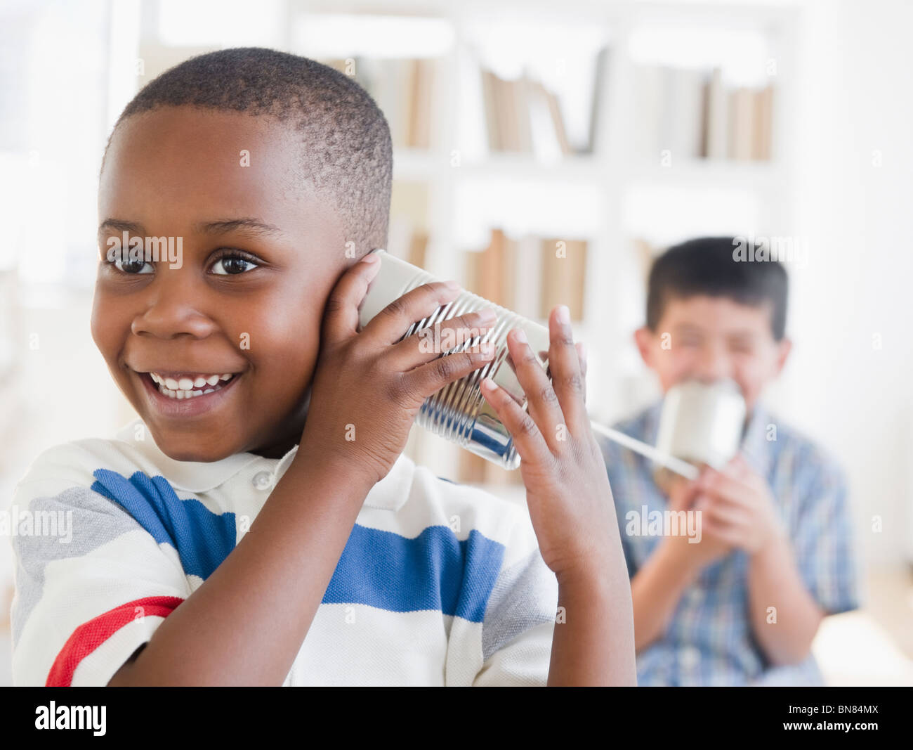 Boys playing with tin can telephone Stock Photo - Alamy