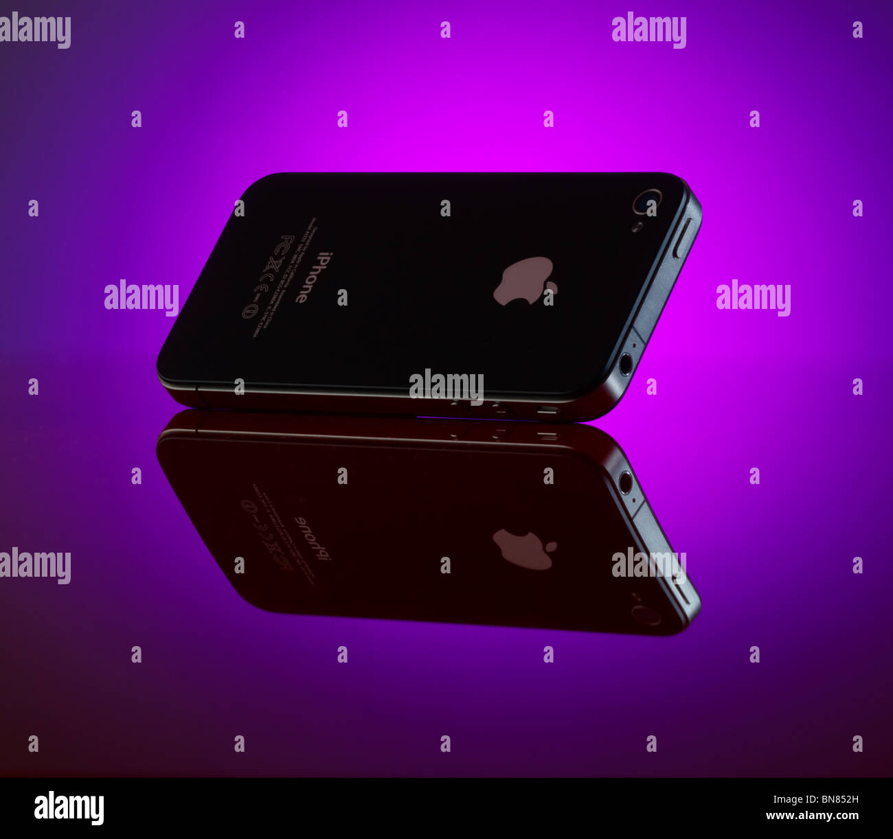 Apple iPhone 4 on a reflective surface with purple glow behind Stock ...