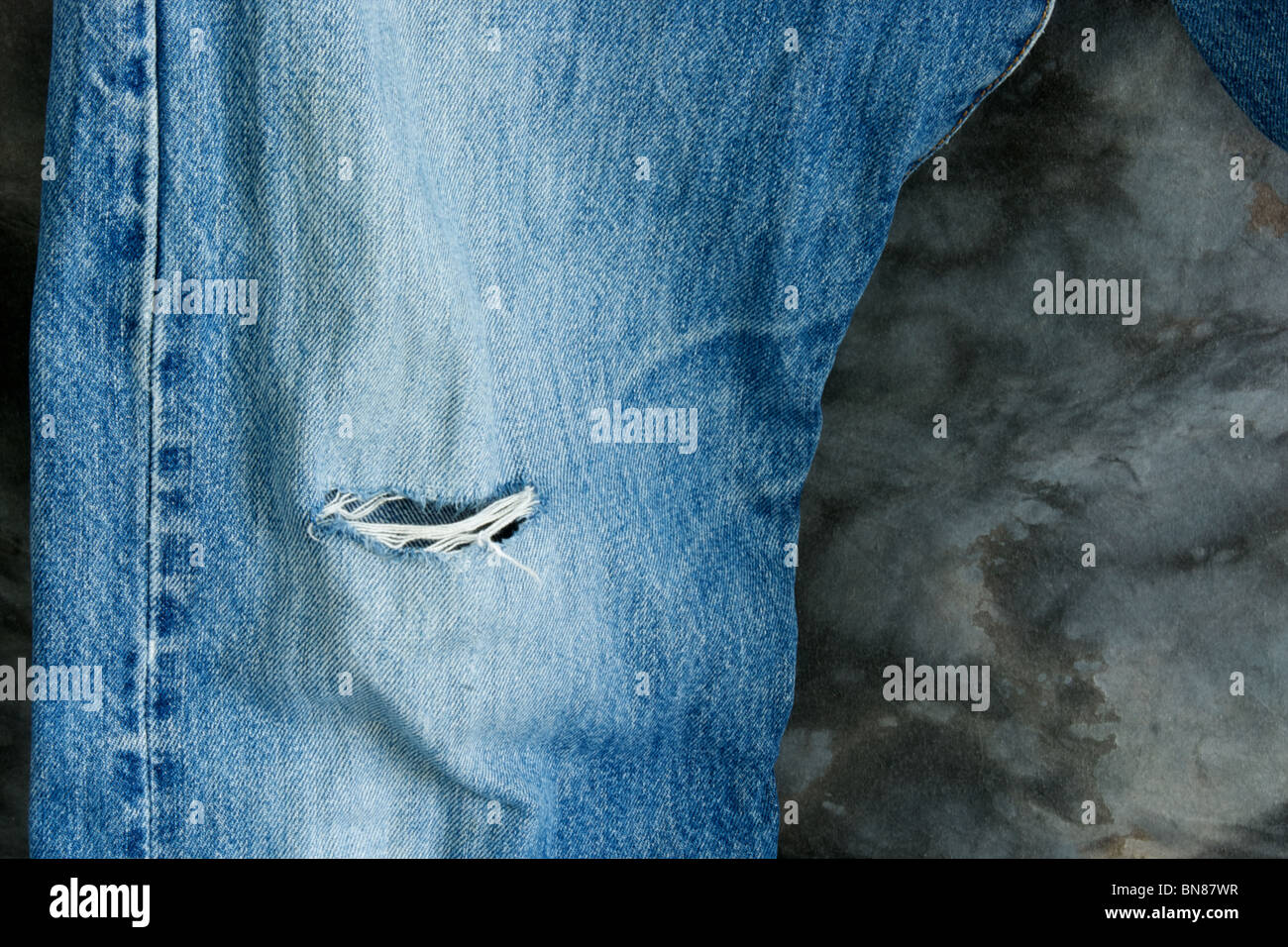 An old pair of blue jeans with a worn out knee showing the frayed ...