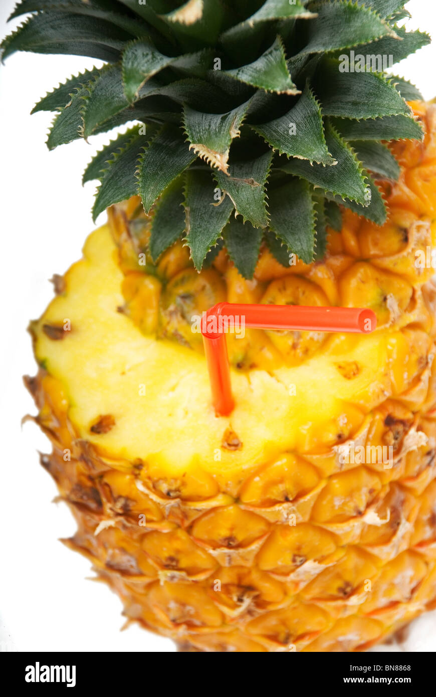 ripe pineapple cutted on top with red and blue straws isolated on white ...