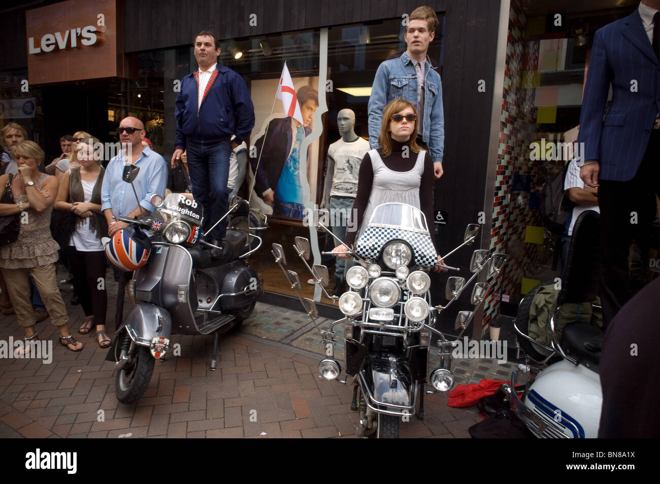A group of Mods standing on their scooters listening to a group during ...