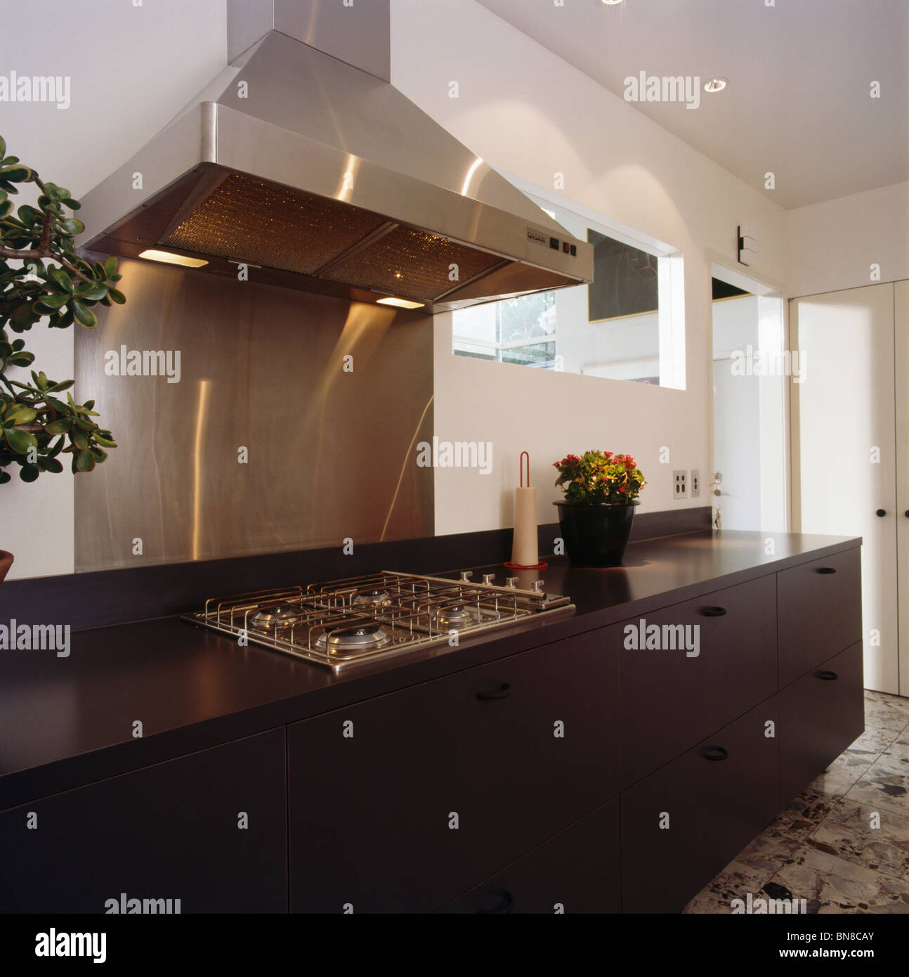 Stainless steel extractor above hob in modern white kitchen with black ...