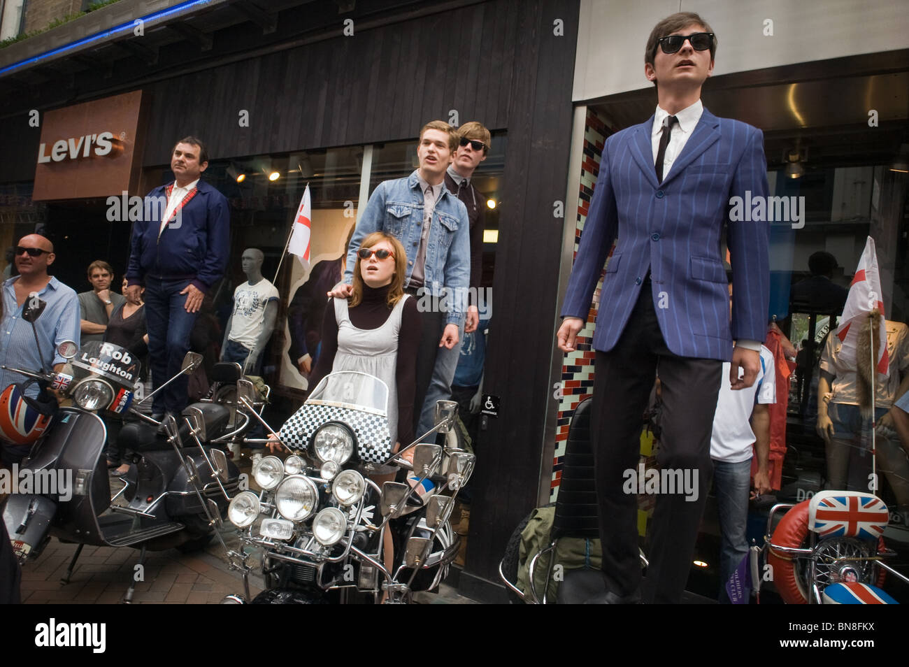 A group of Mods standing on their scooters listening to a group during ...