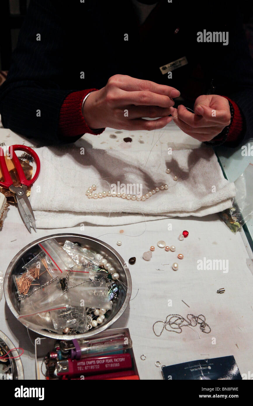 China, Beijing, woman working in a pearl factory showroom Stringing ...