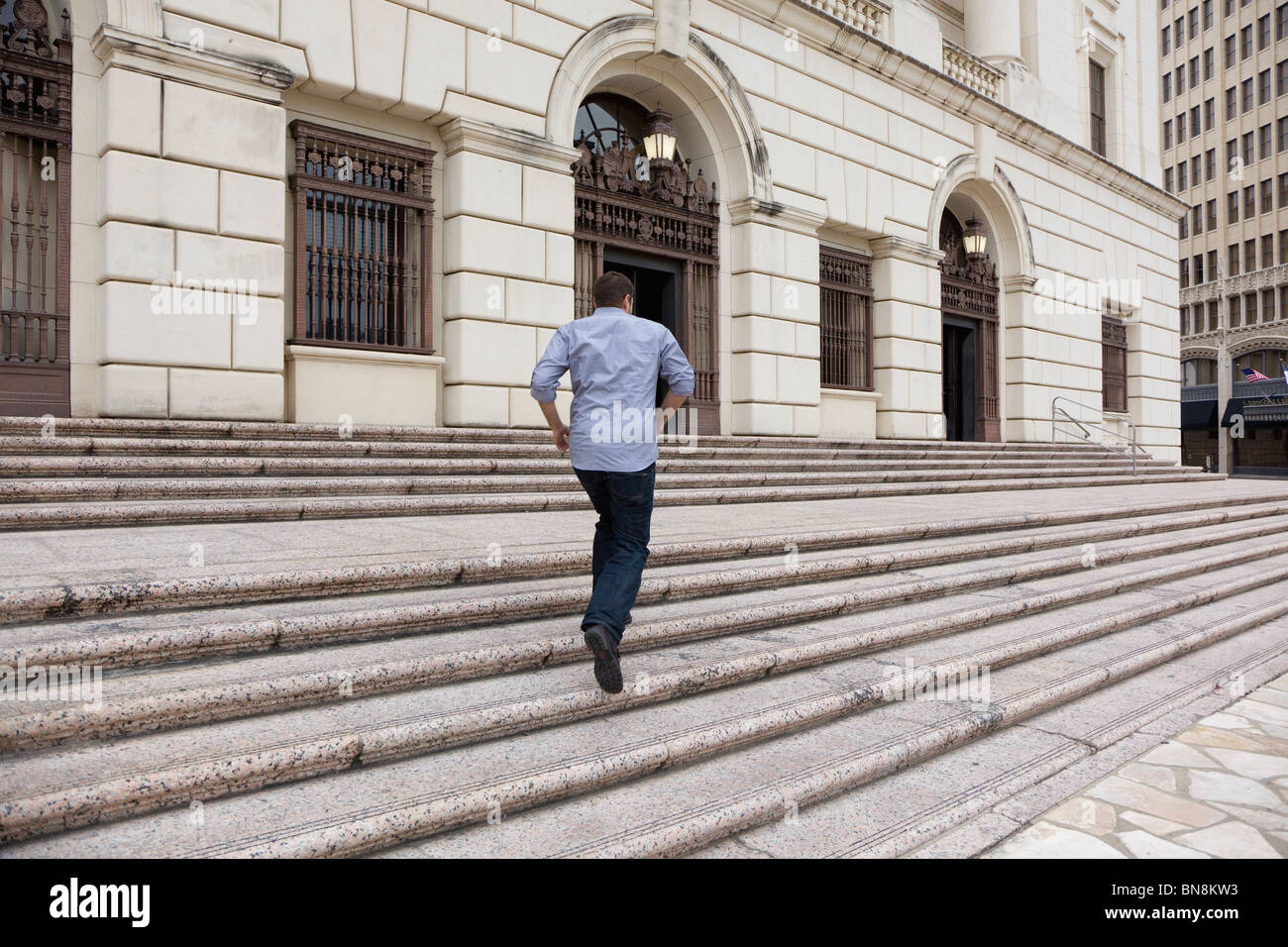 Hispanic man running up steps of urban building Stock Photo - Alamy