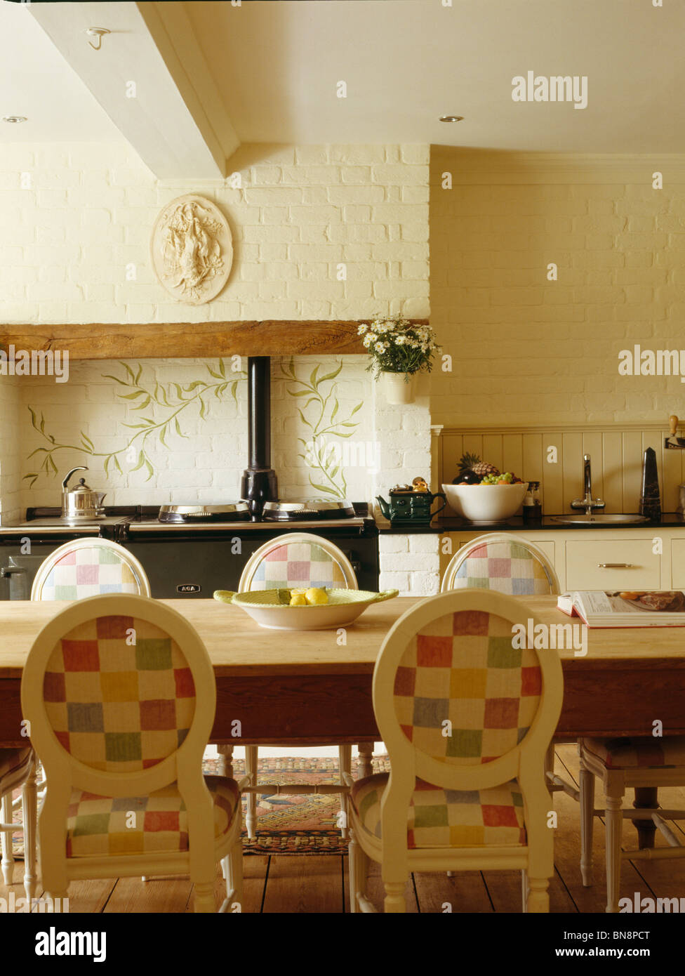 Checked upholstered chairs and old pine table in traditional cream ...
