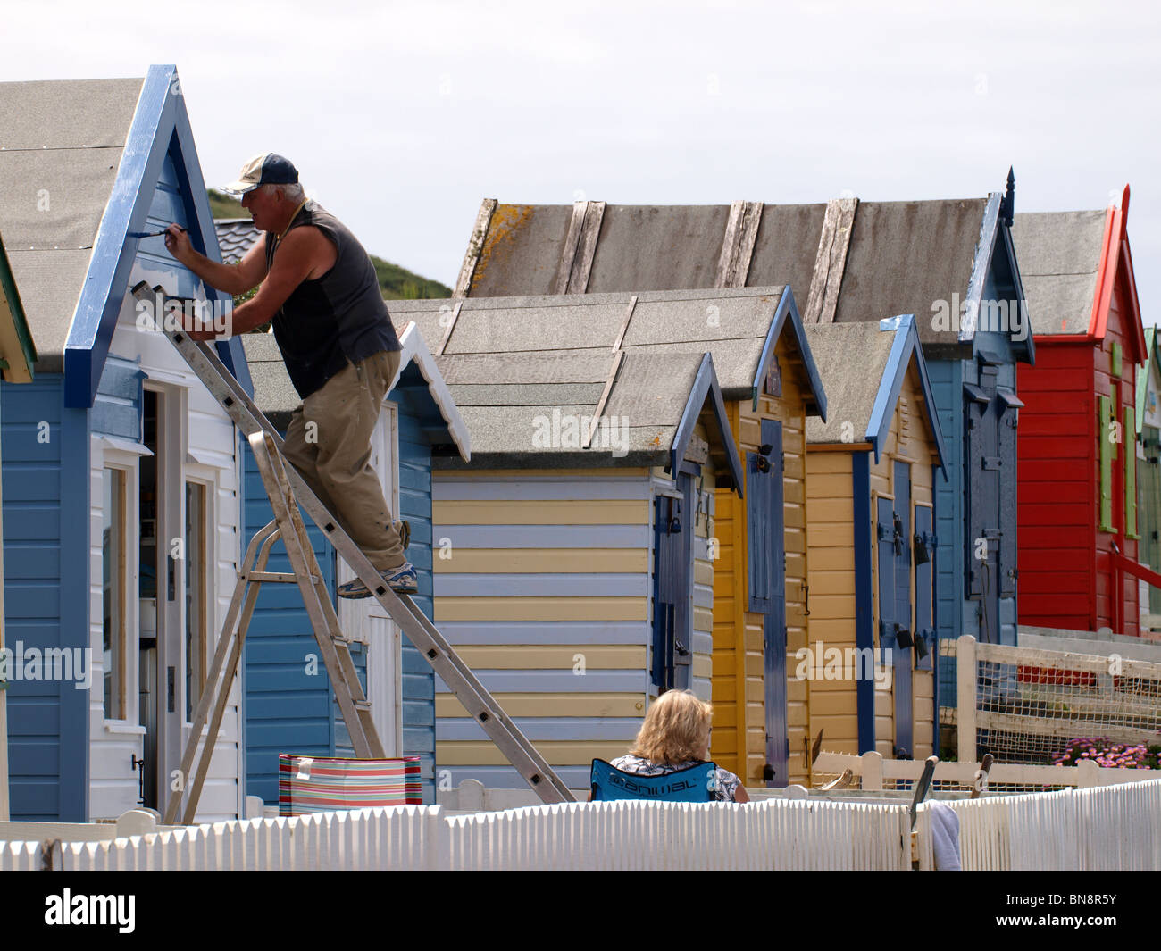 Old man painting beach hut ready for the summer, Westward Ho!, Devon ...