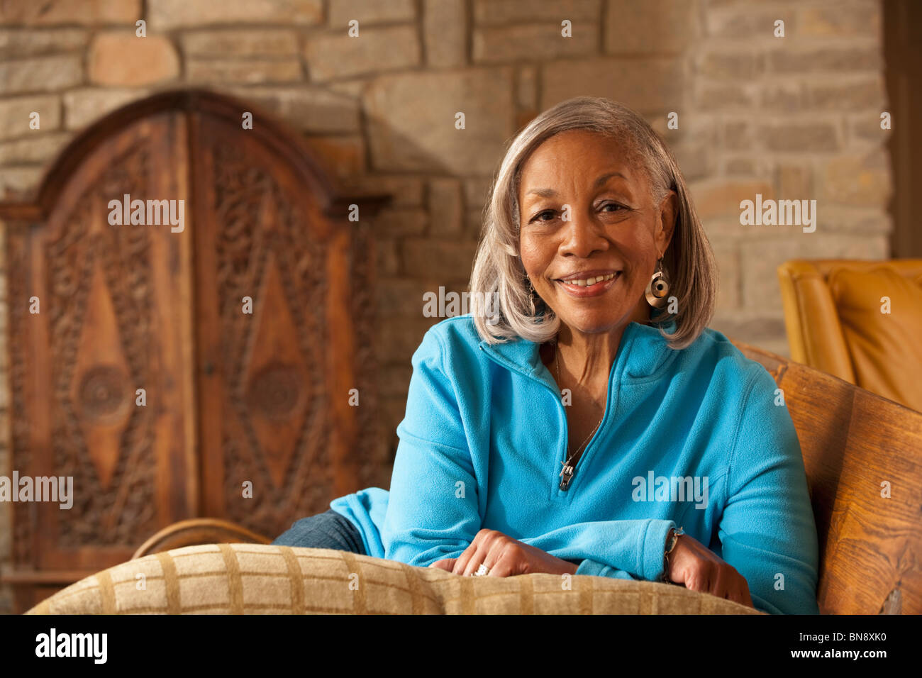 Black woman sitting on sofa Stock Photo - Alamy