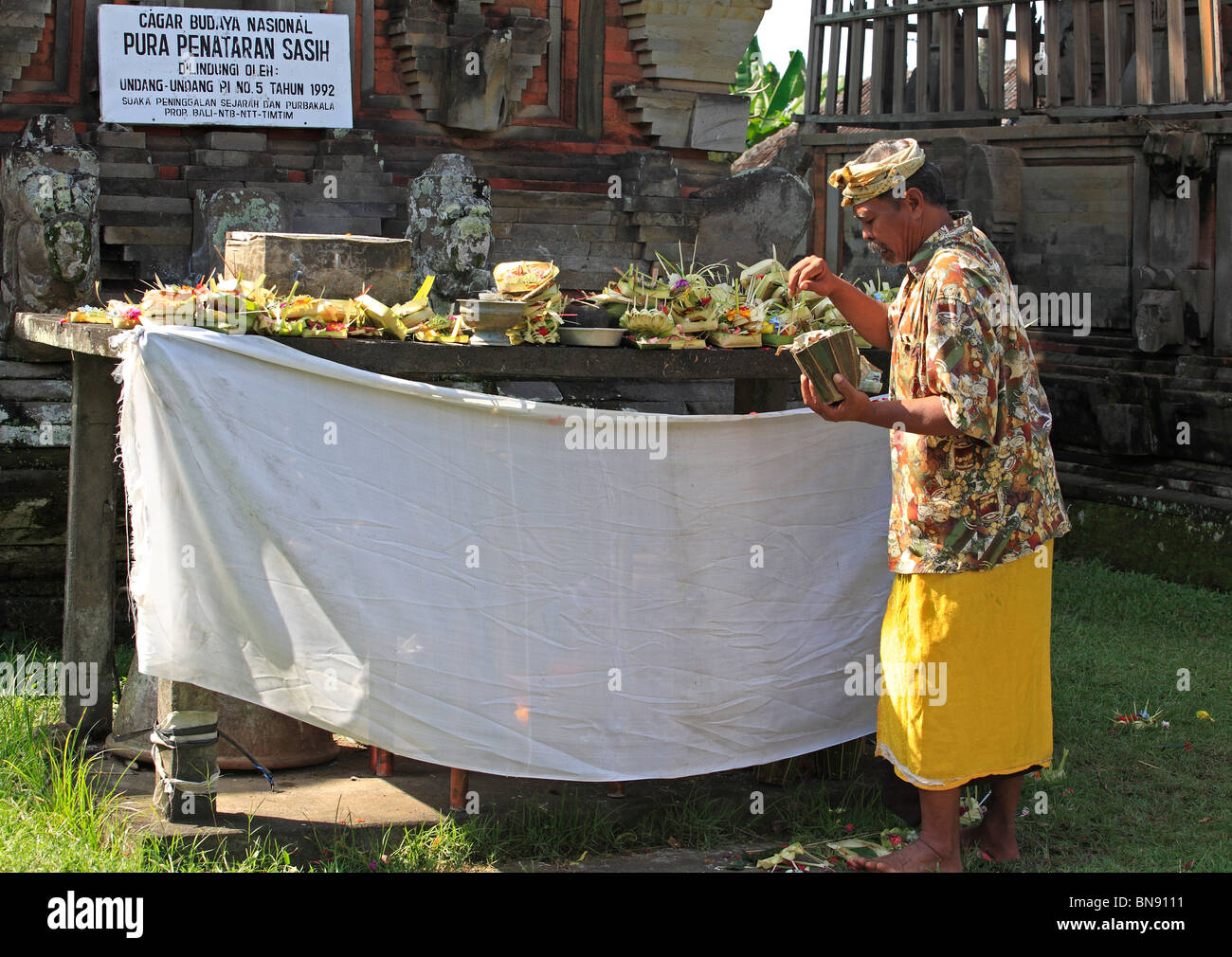 Balinese priest, or holy man collecting money left in offerings made by ...
