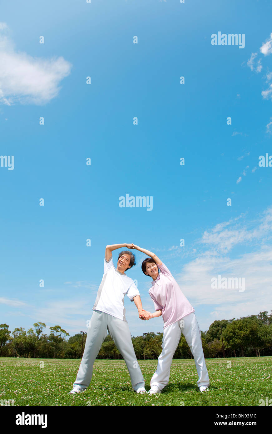 Mature couple in sports clothing stretching Stock Photo - Alamy