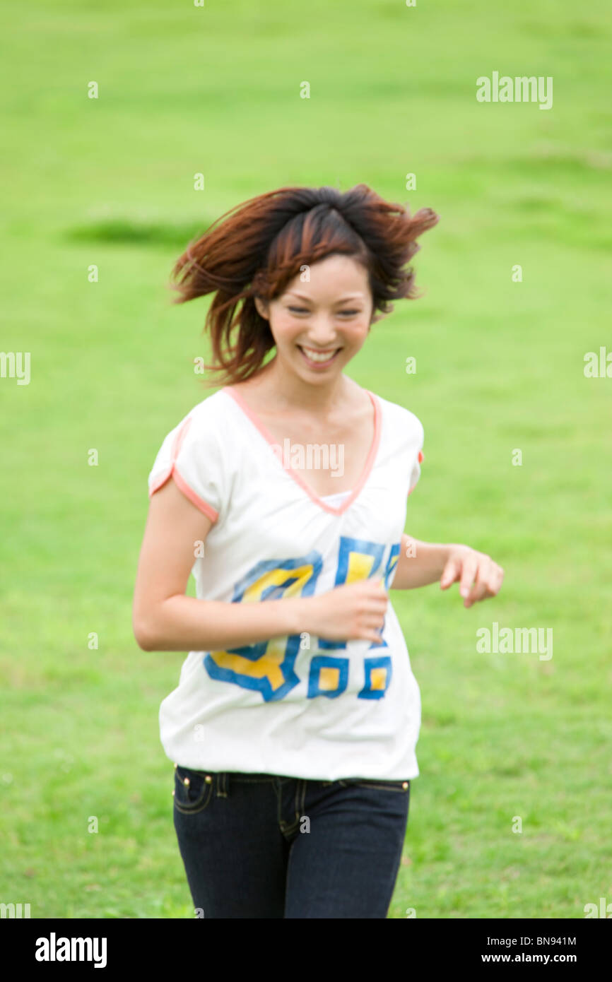 Young Woman Running in Green Field Stock Photo - Alamy