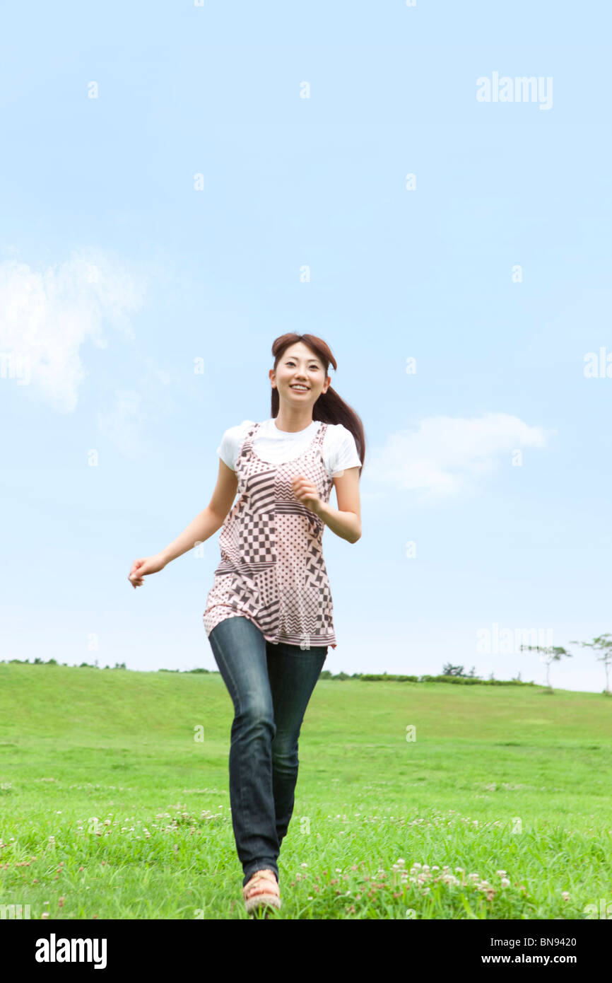 Young Woman Running in Green Field Stock Photo - Alamy