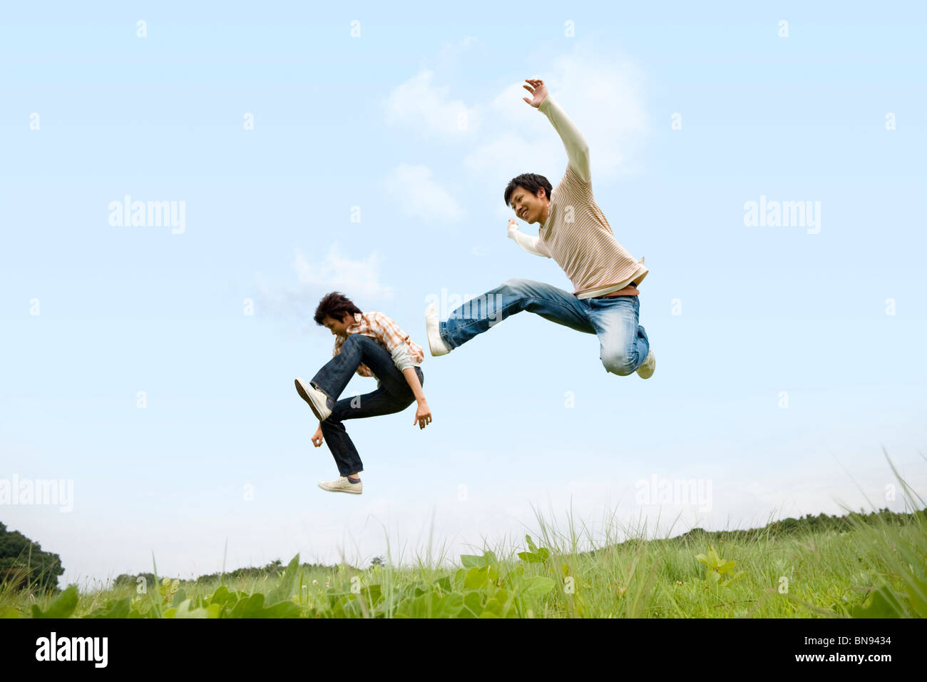 Two Young Men Jumping in Green Field Stock Photo - Alamy