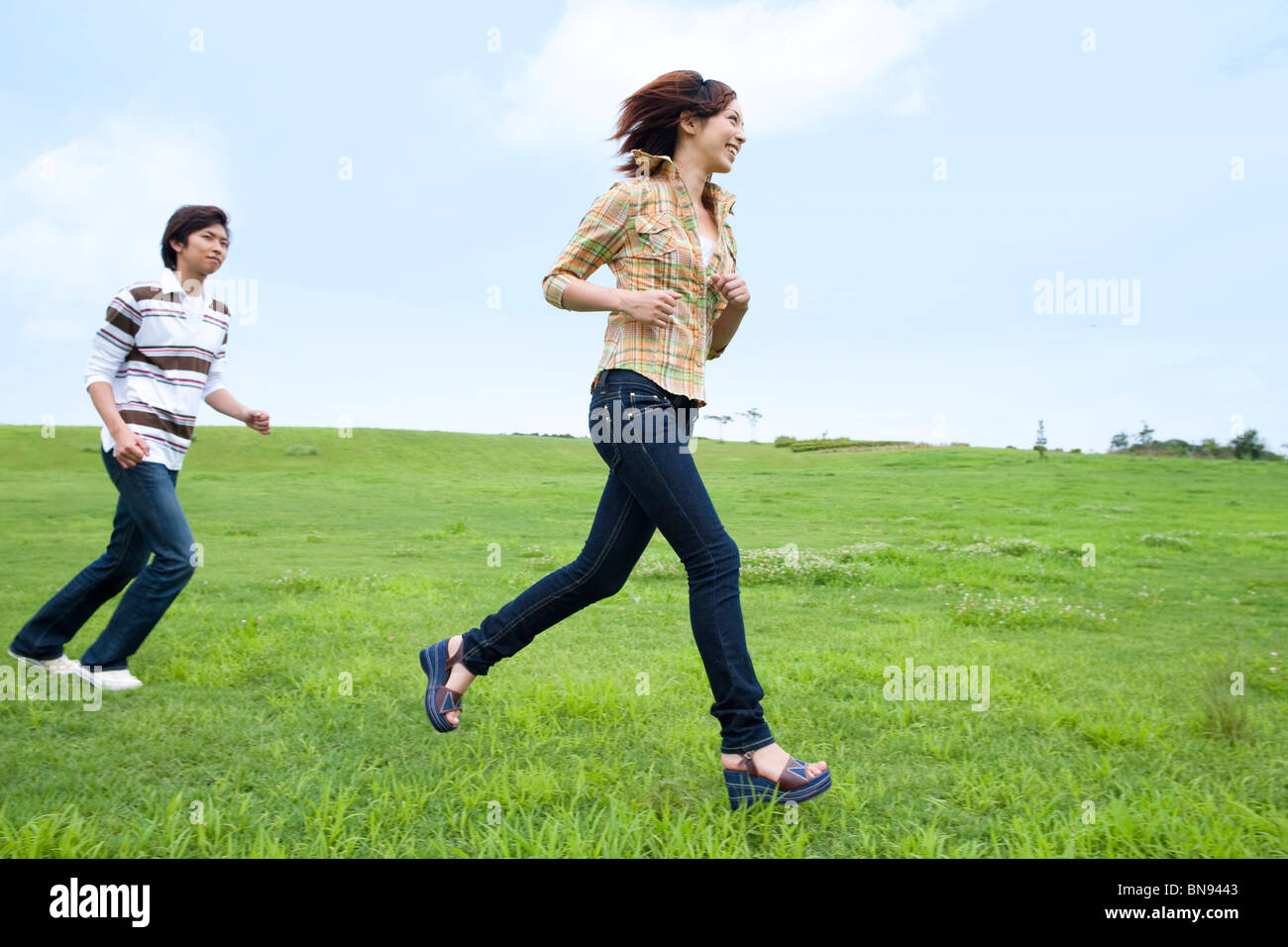 Young Man and Woman Running in Green Field Stock Photo - Alamy