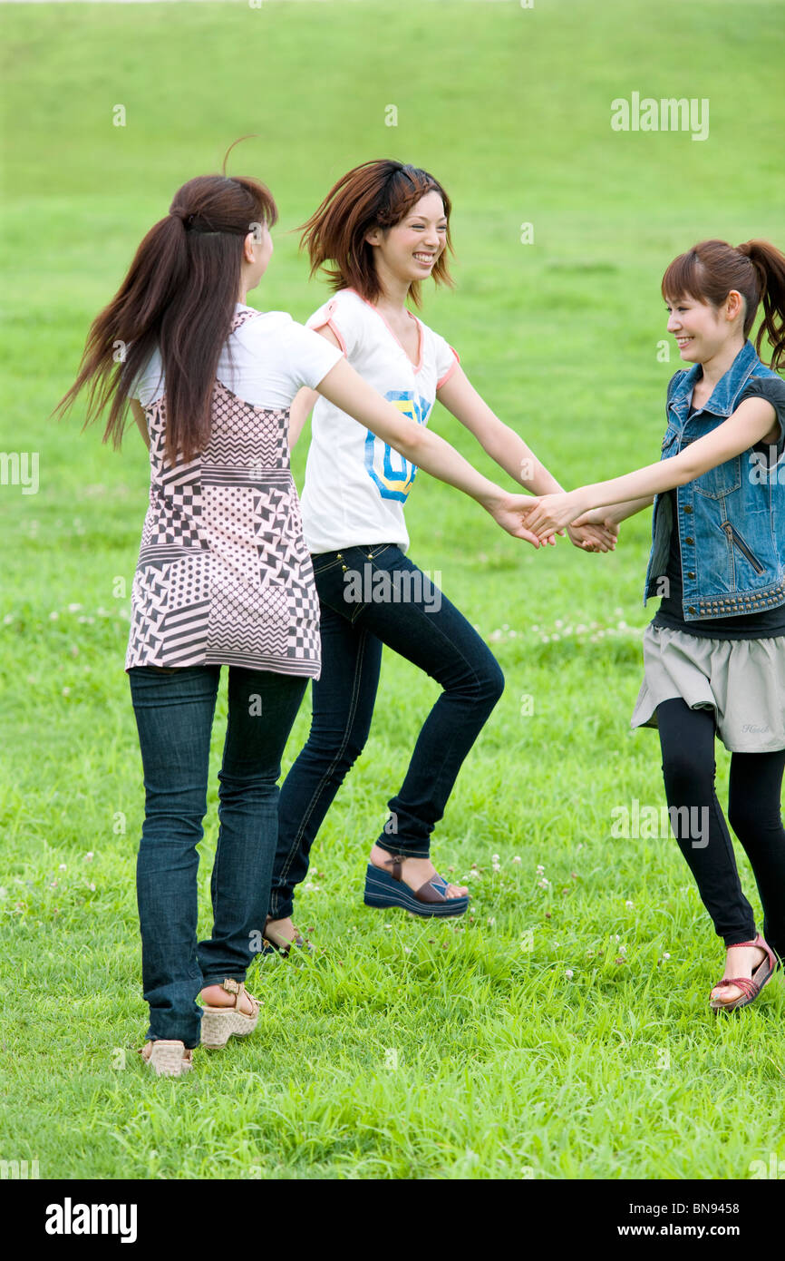Three Women Holding Hands Dancing Around Stock Photo - Alamy