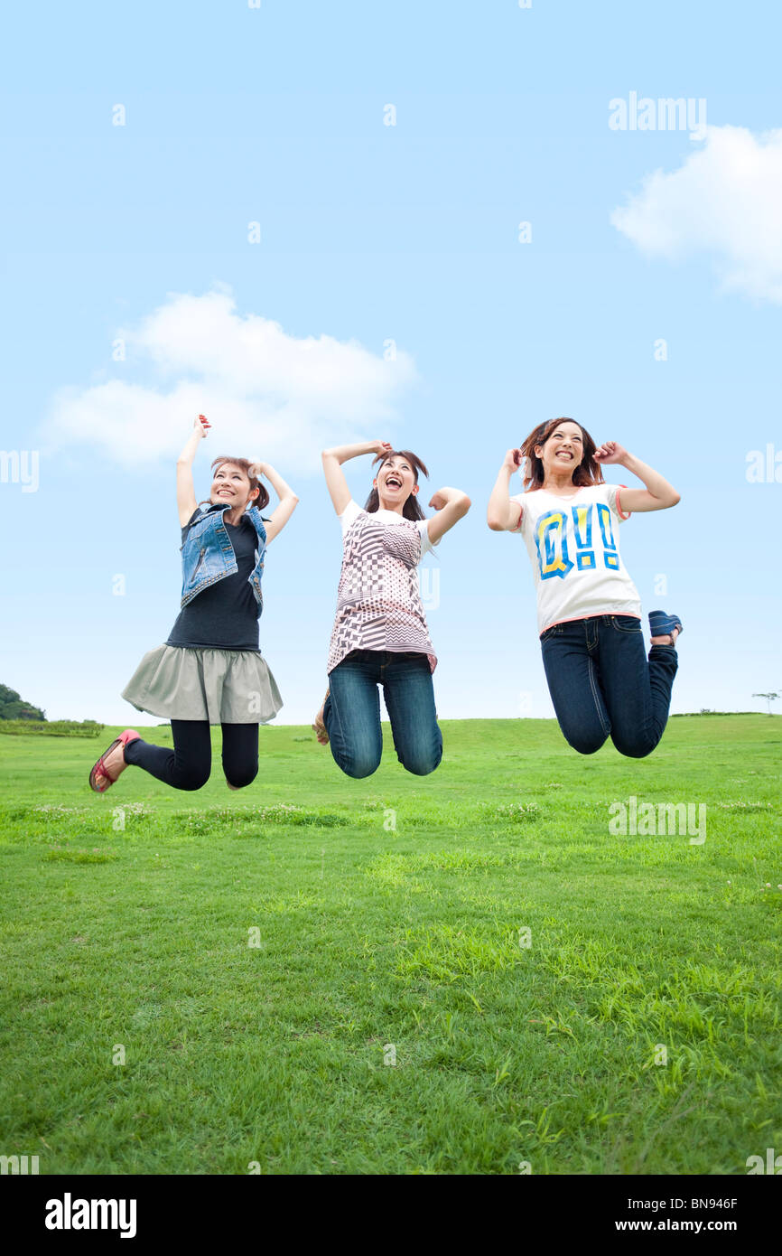 Three Young Women Jumping in Green Field Stock Photo - Alamy