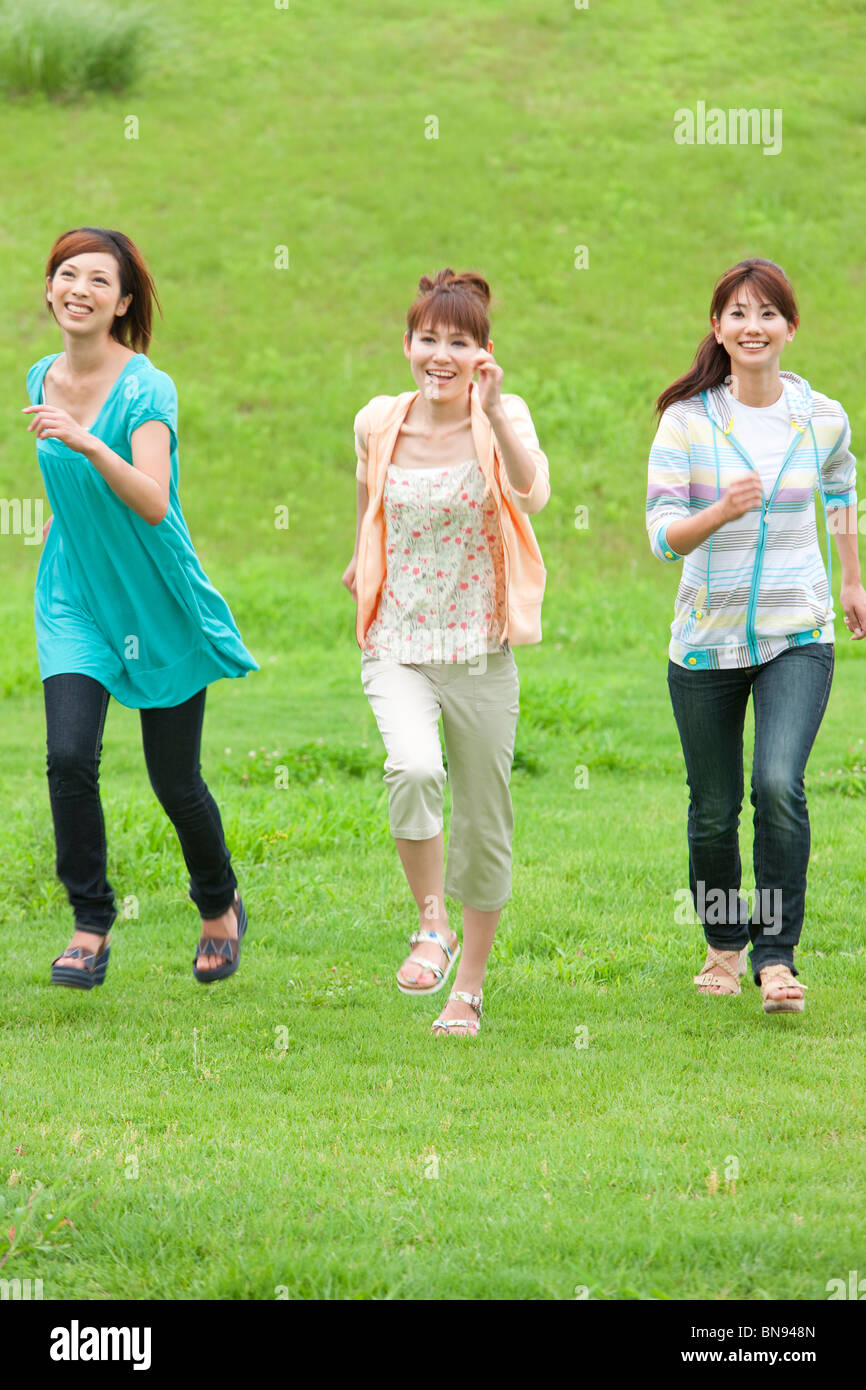 Three Young Women Running in Green Field Stock Photo - Alamy