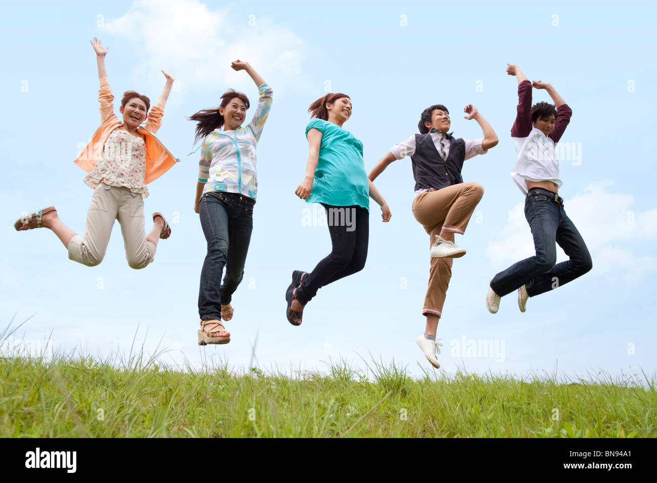 Five young people jumping in field Stock Photo - Alamy