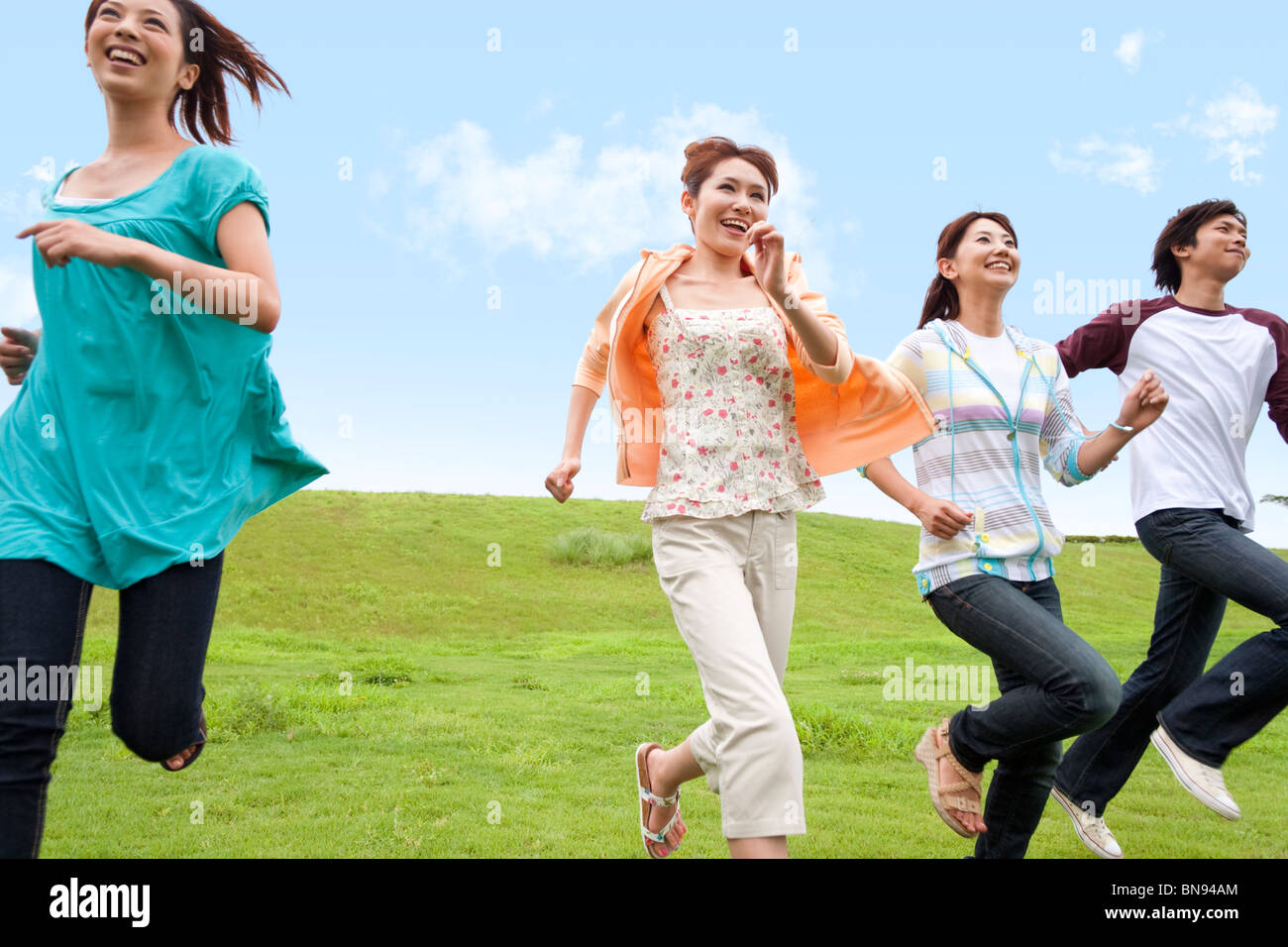 Four young people running in field Stock Photo - Alamy