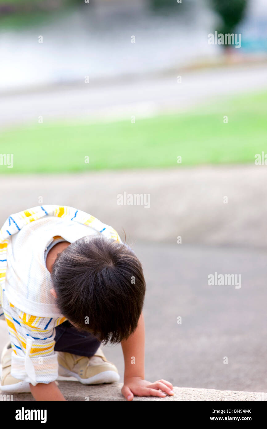 Boy crouching on road differential focus Stock Photo - Alamy
