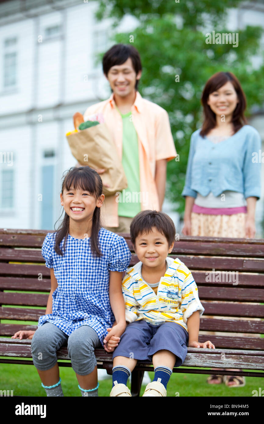 Portrait of family children sitting on bench smiling Stock Photo - Alamy