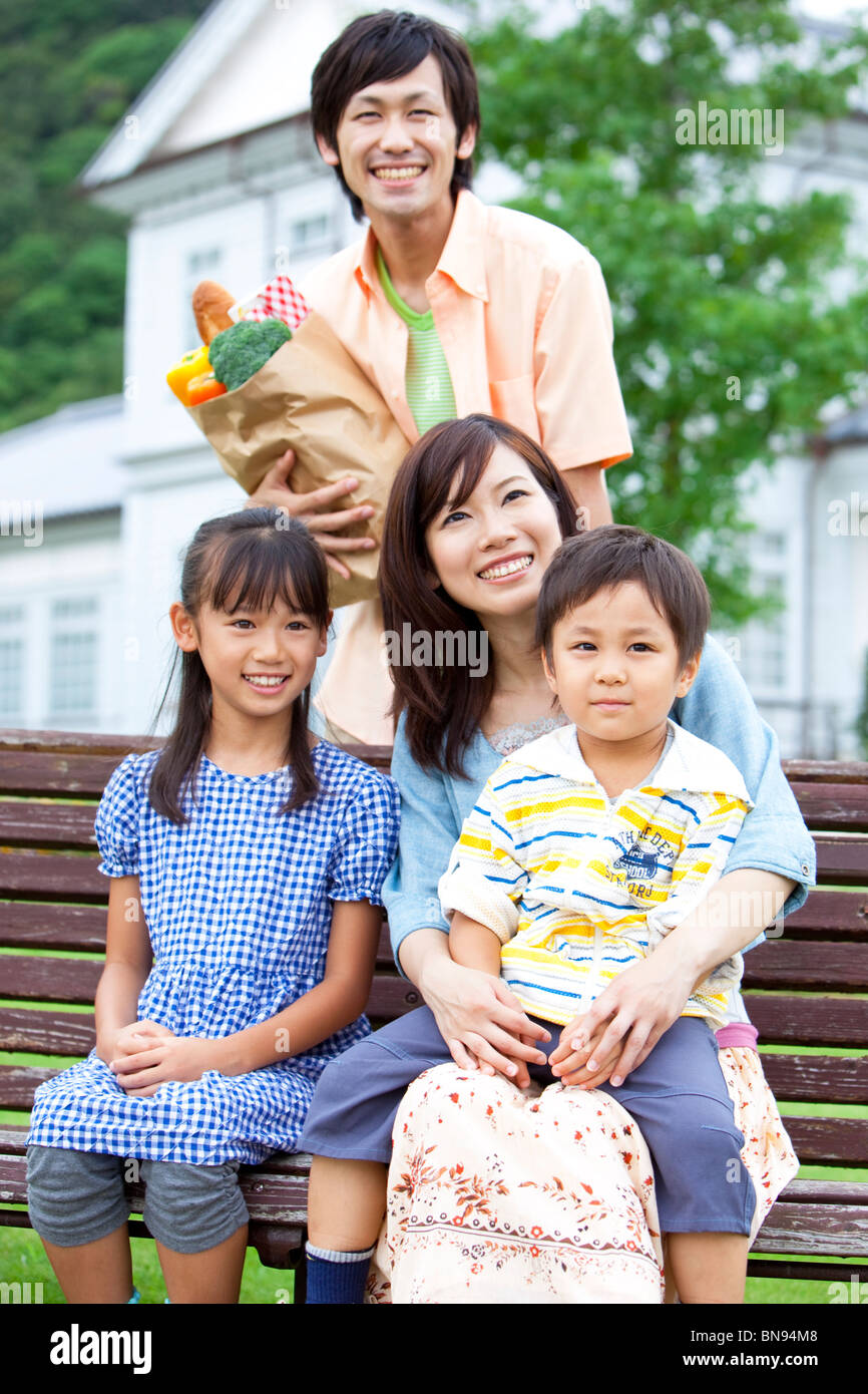 Portrait of family sitting on bench smiling Stock Photo - Alamy