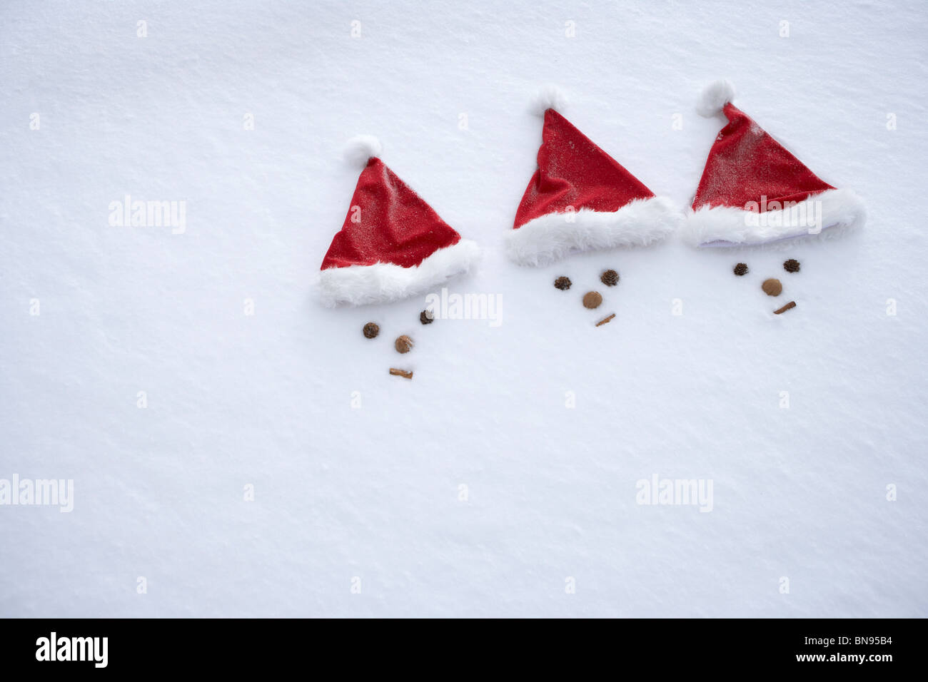 Faces in snow wearing Santa hats Stock Photo - Alamy