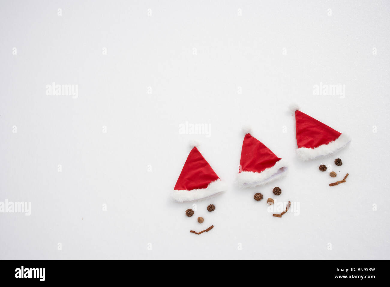 Faces in snow wearing Santa hats Stock Photo - Alamy