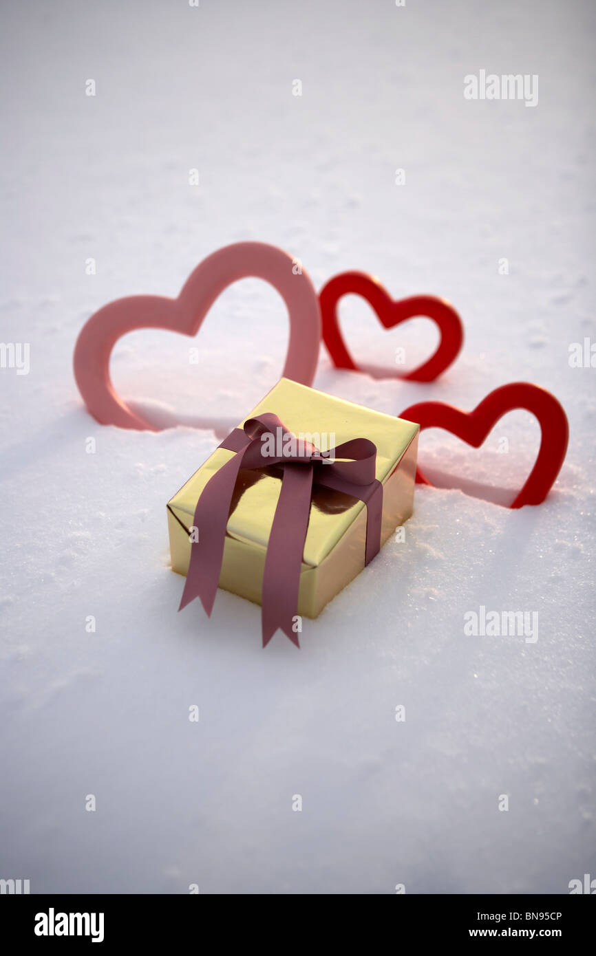 Present in snow with heart shapes Stock Photo - Alamy