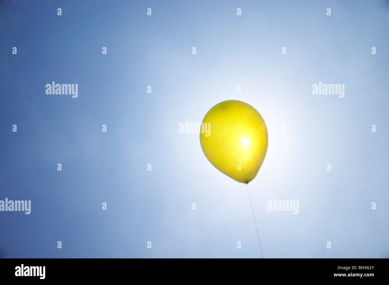 A single yellow balloon floating in the sky Stock Photo - Alamy
