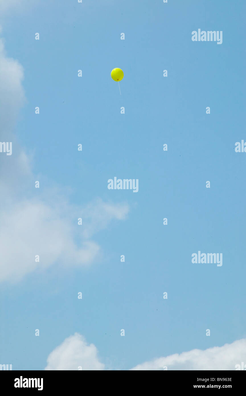 A single yellow balloon floating in the sky Stock Photo - Alamy